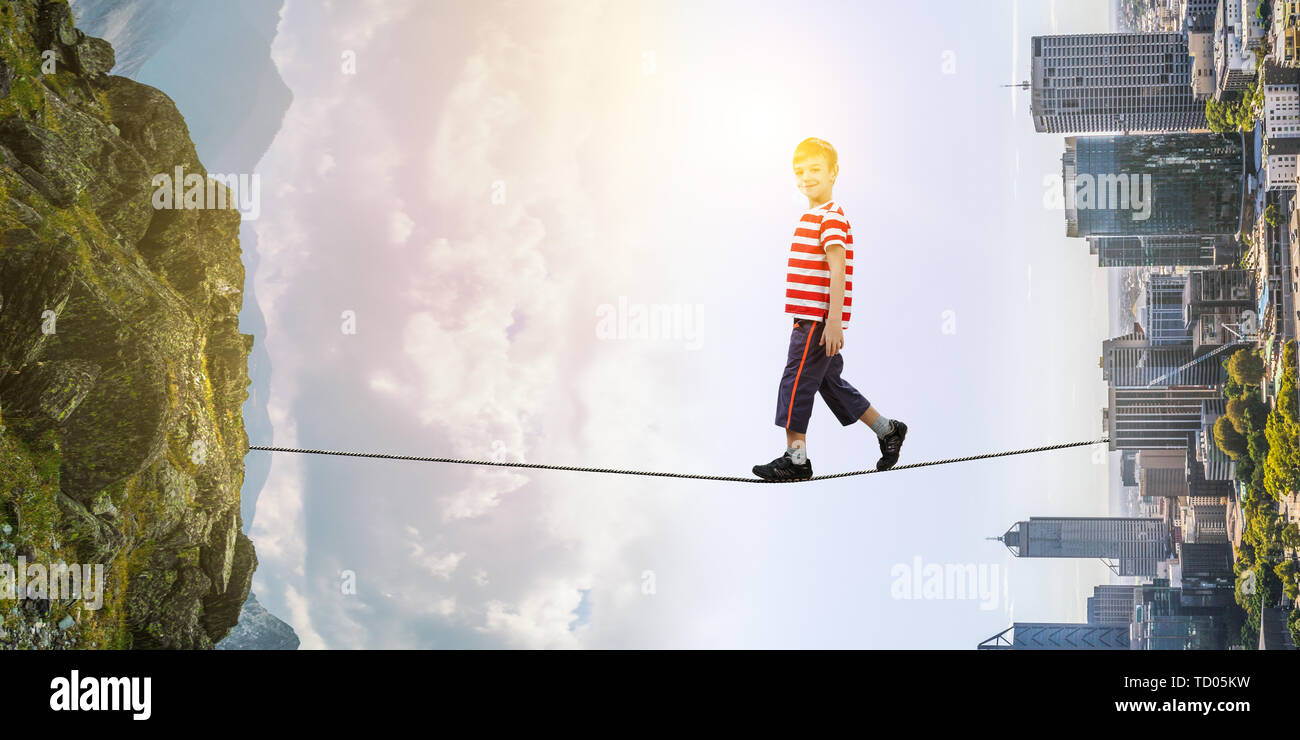 Cute joyful little boy walking on a rope. Mixed media Stock Photo - Alamy