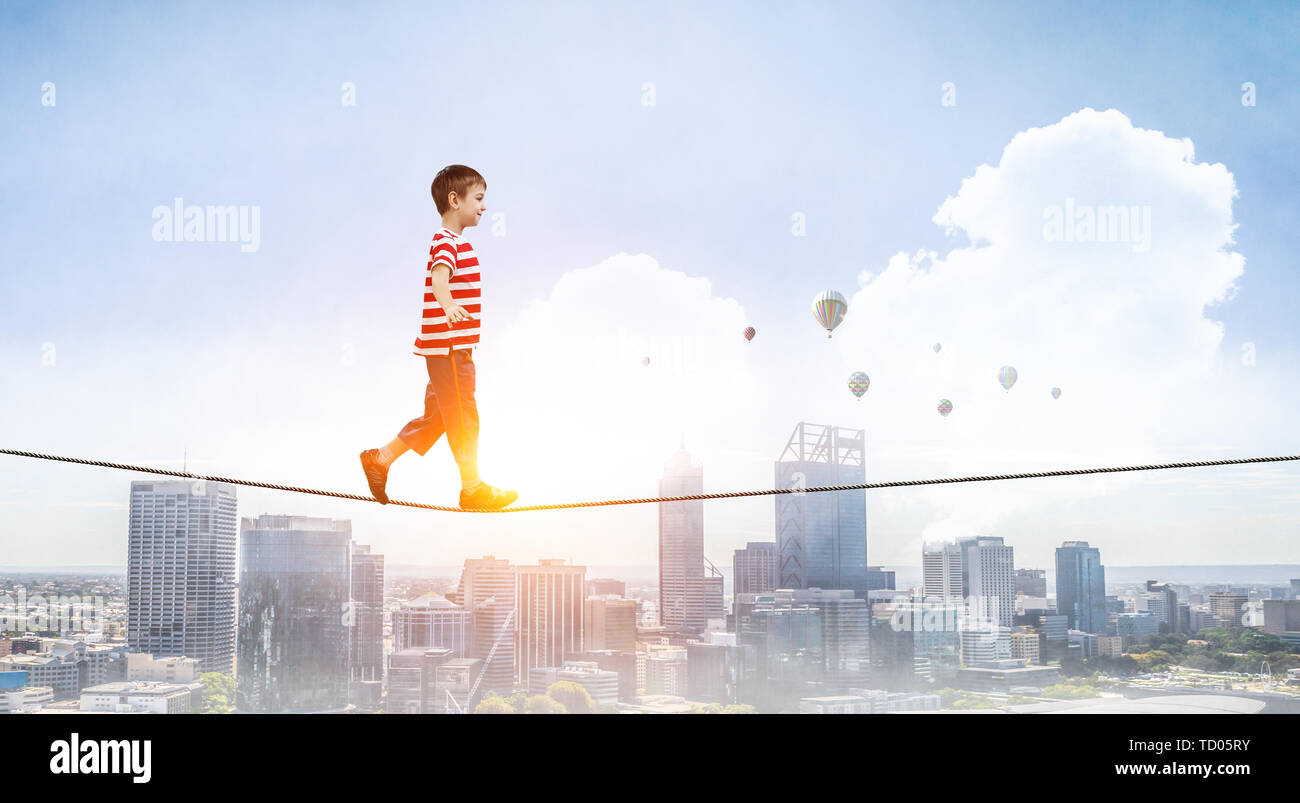 Cute joyful little boy walking on a rope over city. Mixed media Stock ...