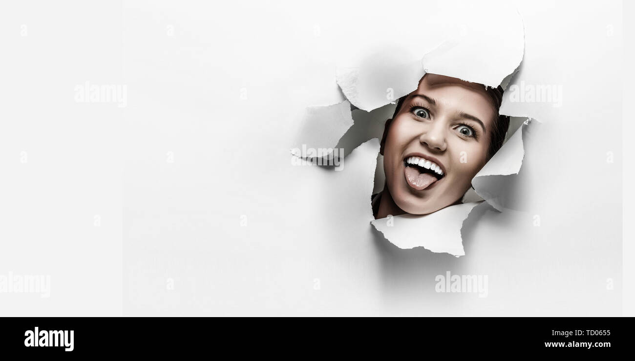 Woman looking out from a hole of torn paper Stock Photo - Alamy