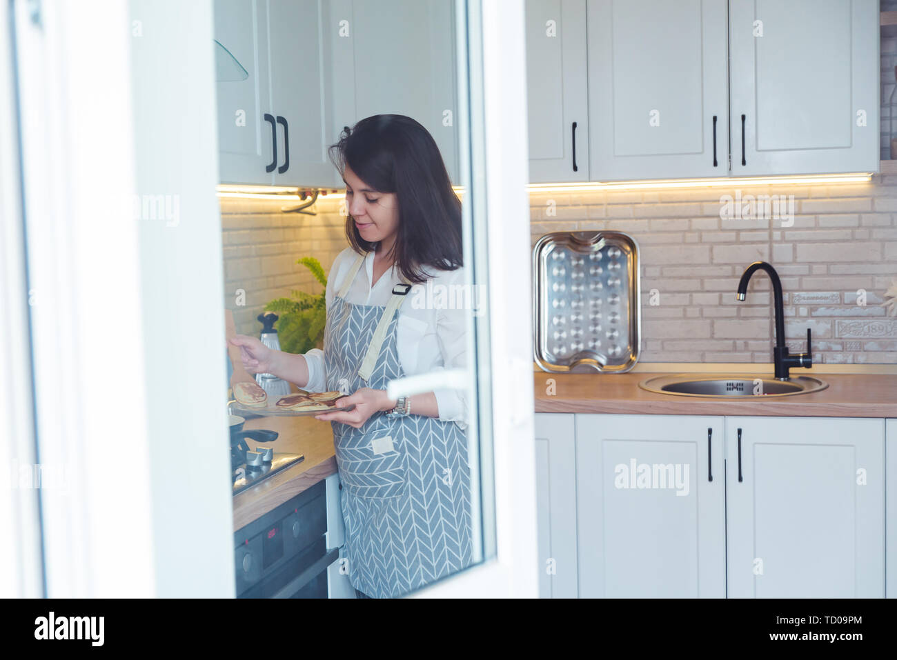 woman cooking pancakes view through window Stock Photo - Alamy