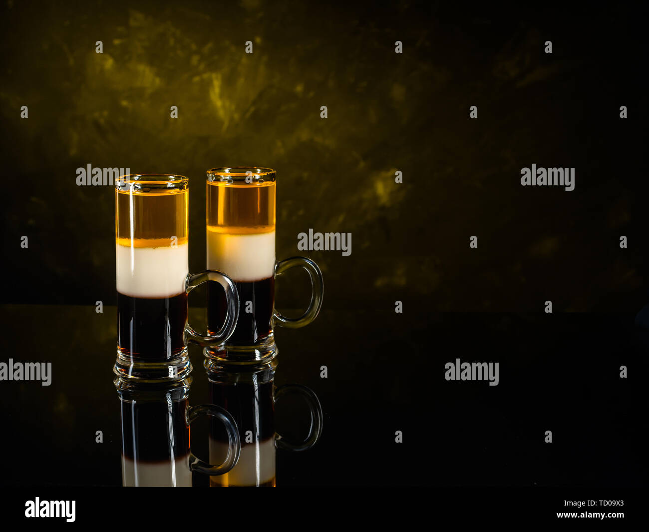 Two B-52 cocktails shot on black mirror surface and wall background ...