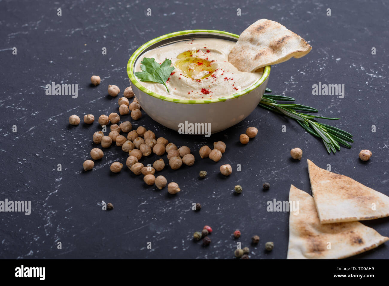 Homemade hummus, chickpea beans, rosemary with pita on black stone ...