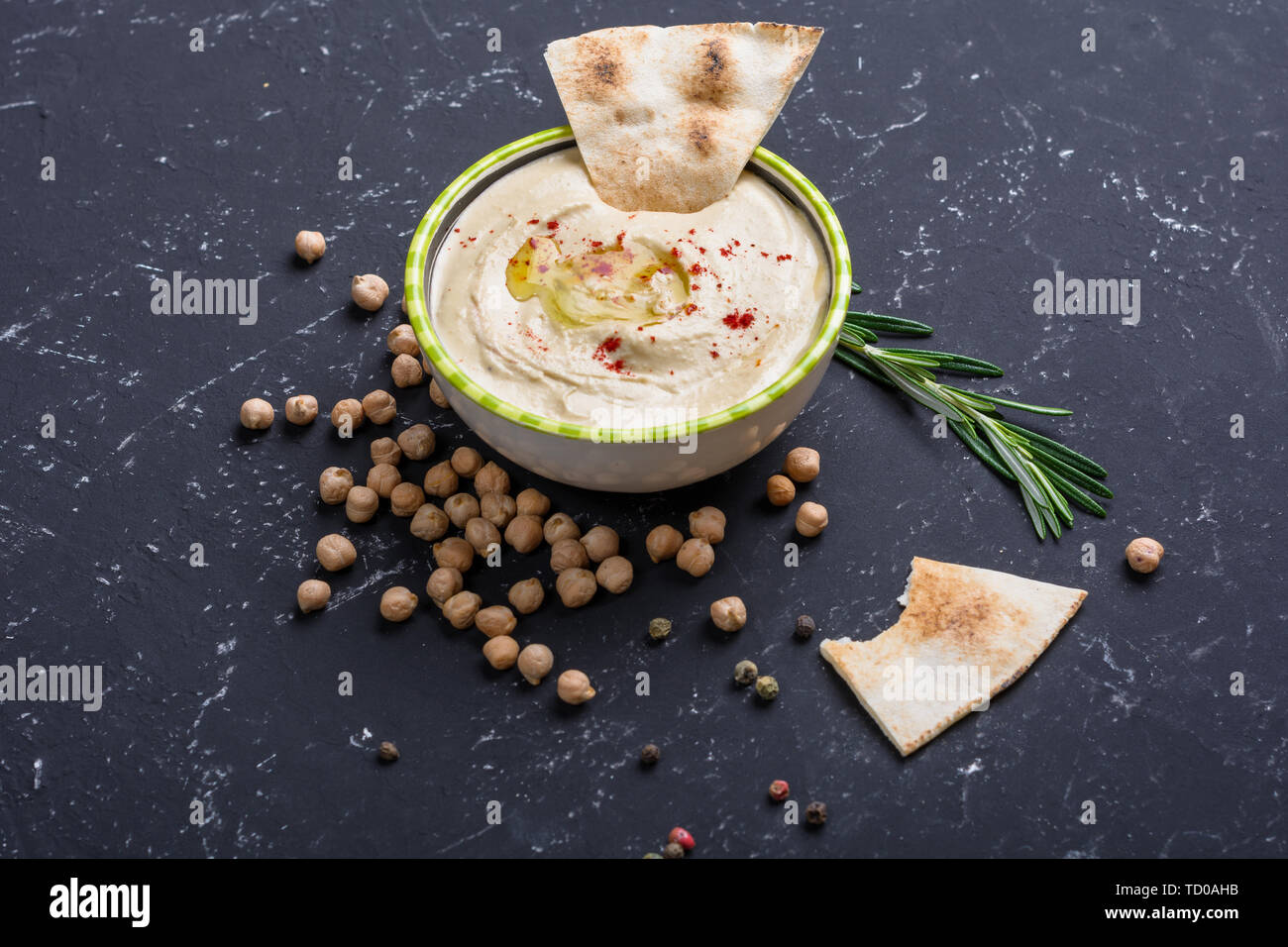Homemade hummus, chickpea beans, rosemary with pita on black stone ...