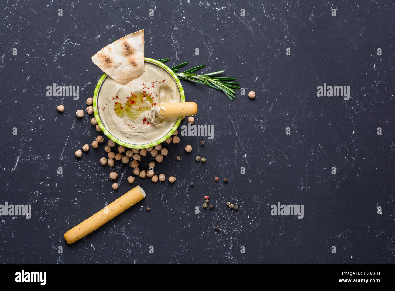 Homemade hummus with pita and grissini bread stick on black stone table ...