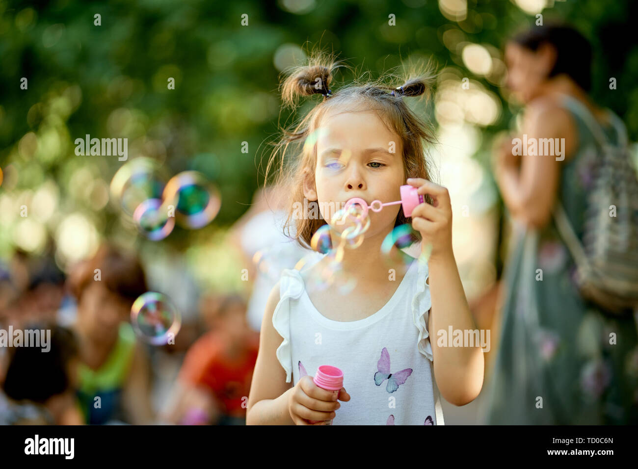Little cute baby girl is making soap bubbles in the park on beautiful ...