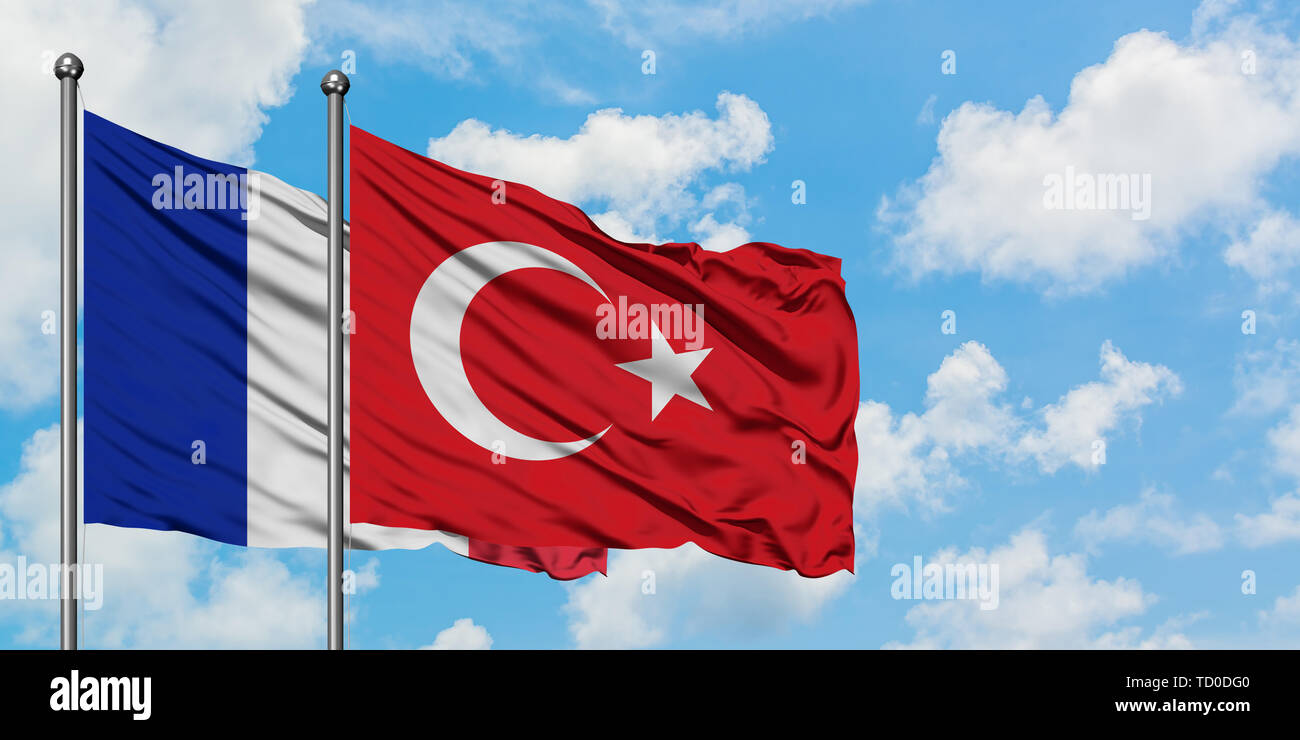France and Turkey flag waving in the wind against white cloudy blue sky ...