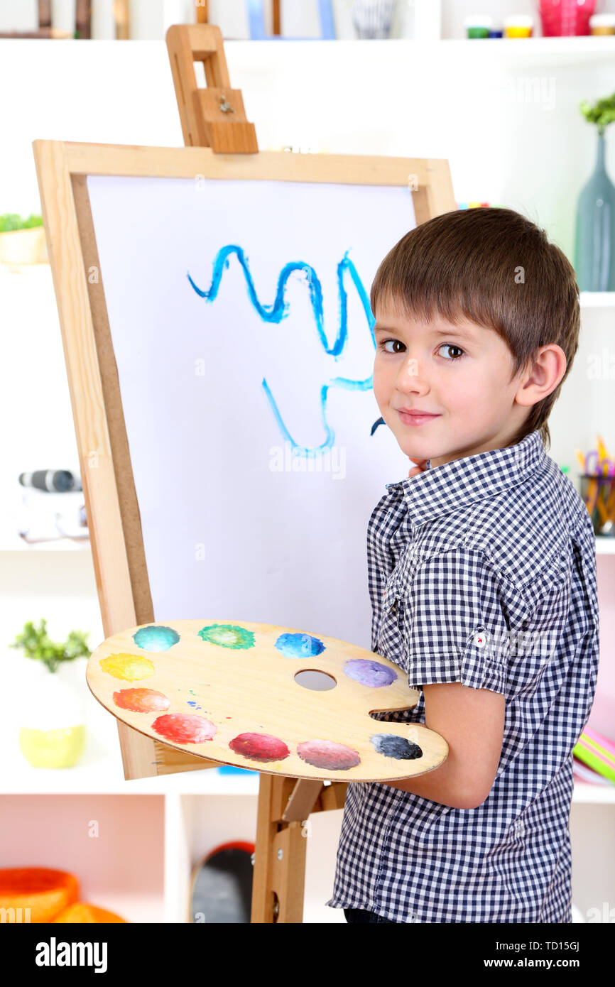 Little boy painting paints picture on easel Stock Photo - Alamy