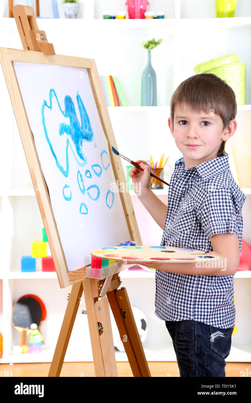 Little boy painting paints picture on easel Stock Photo Alamy