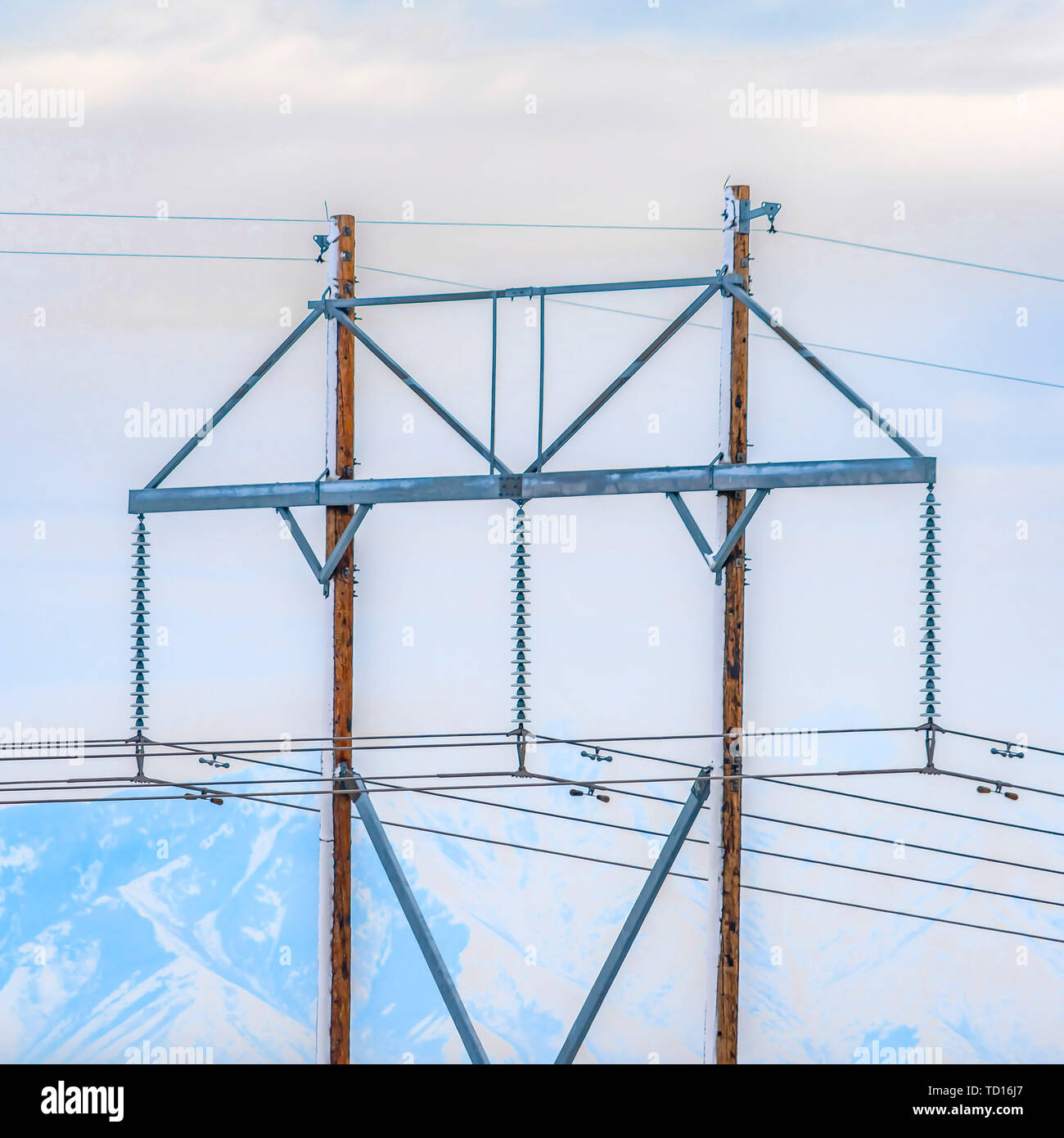 Square Overhead power lines with snowy mountain and cloud filled sky ...