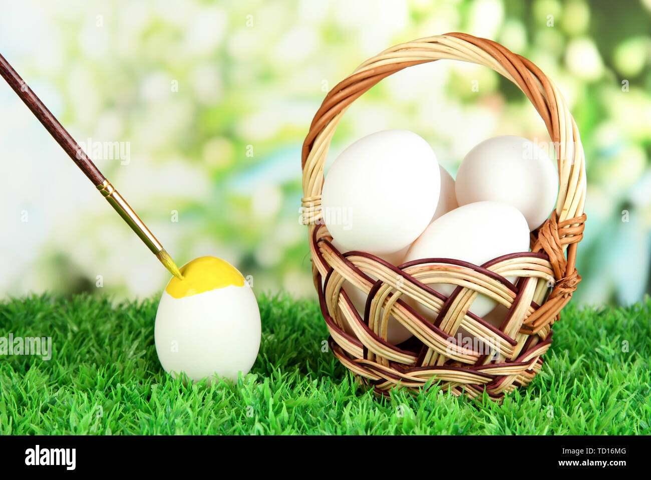 Easter eggs in basket on grass on bright background Stock Photo - Alamy