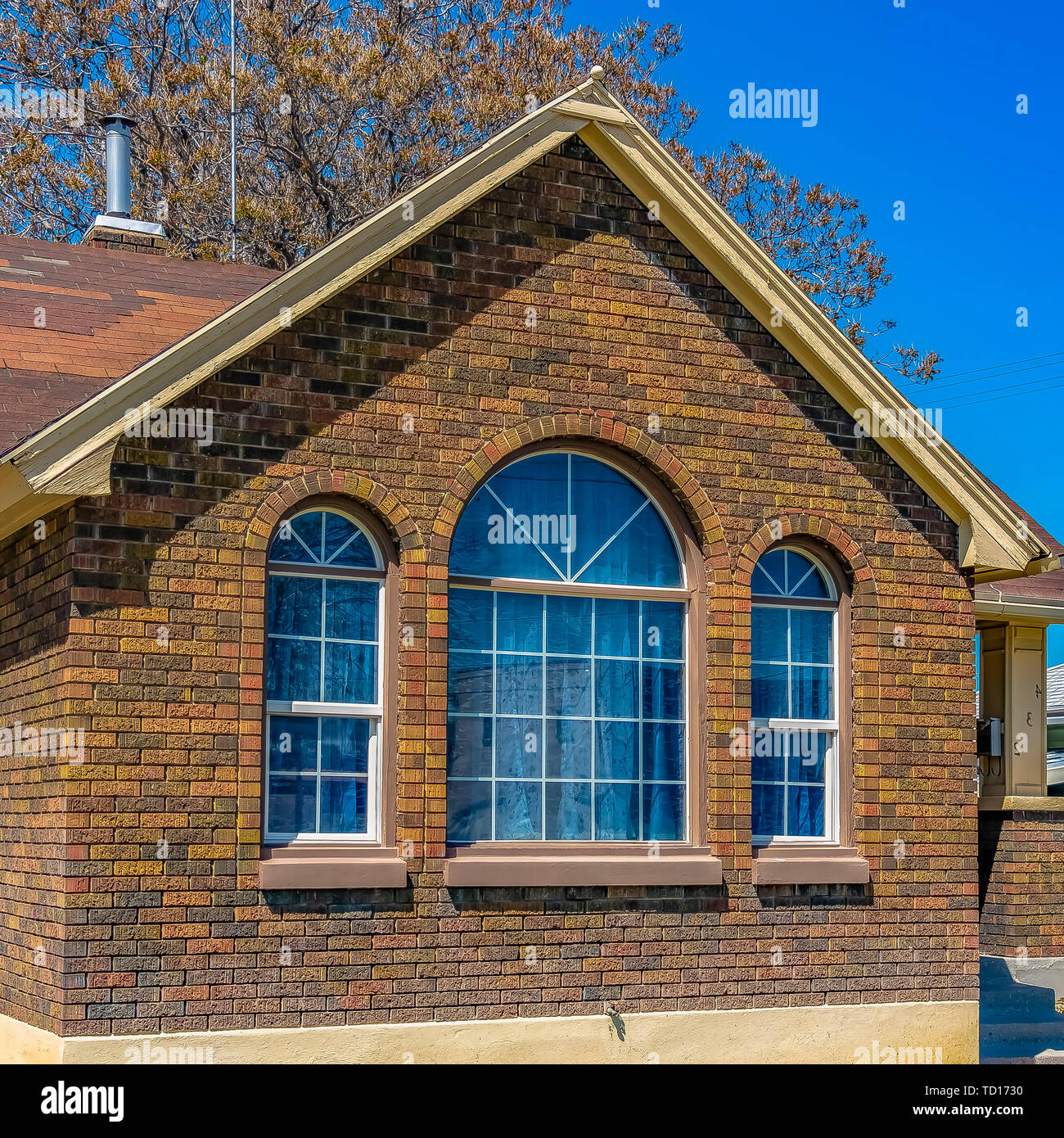Square Exterior of a home with stone brick wall against trees and ...