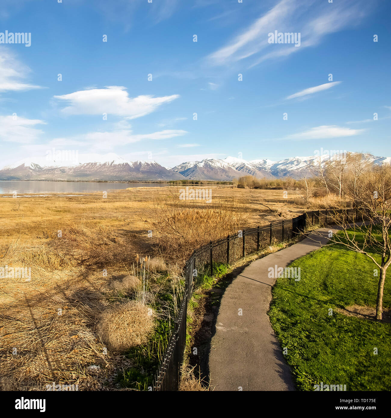 Square Paved pathway and fence along the shore of a lake with brown ...