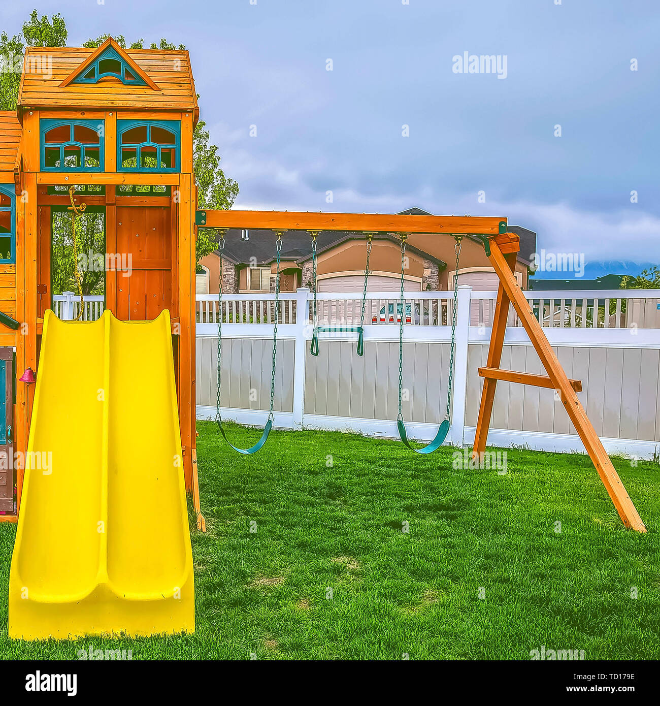 Square frame Playground on a backyard with view of homes and cloudy sky ...