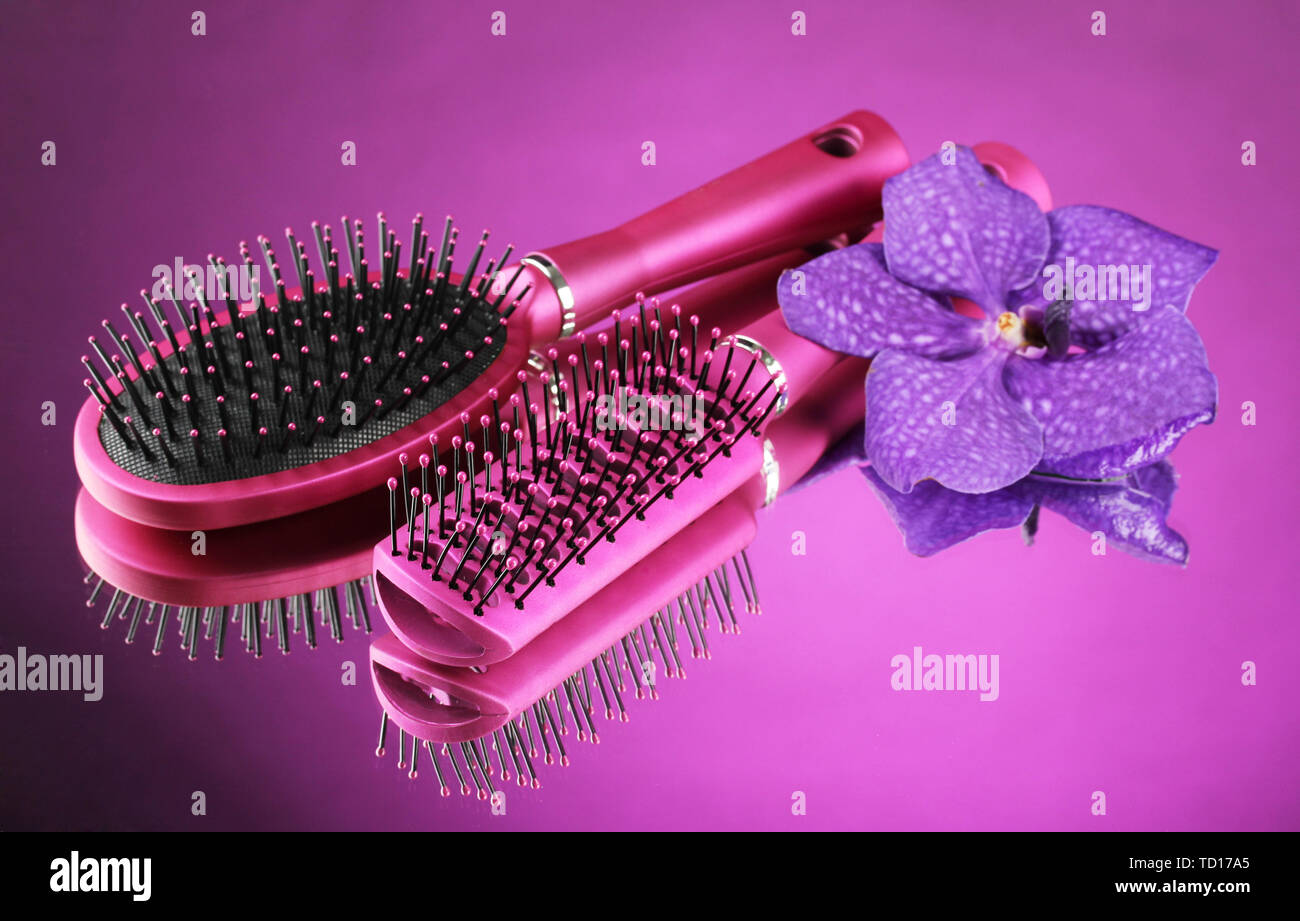 Comb brushes and flower on purple background Stock Photo - Alamy