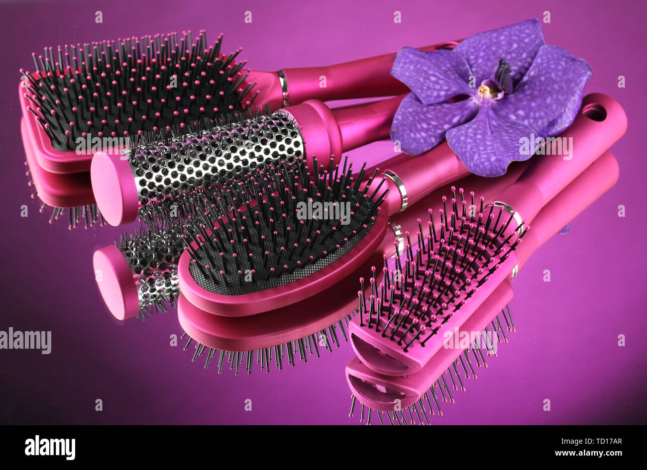 Comb brushes and flower on purple background Stock Photo - Alamy