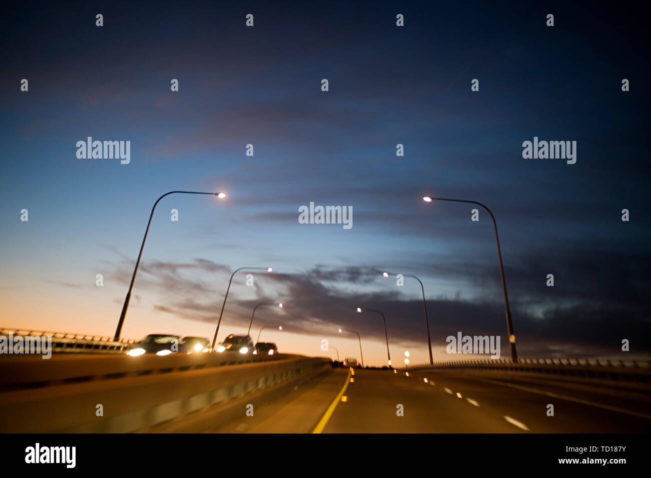 Illuminated street lights over a highway at dusk Stock Photo - Alamy