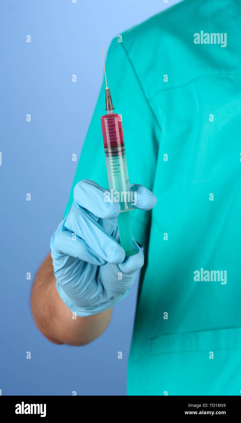 Doctor with syringe on blue background Stock Photo - Alamy