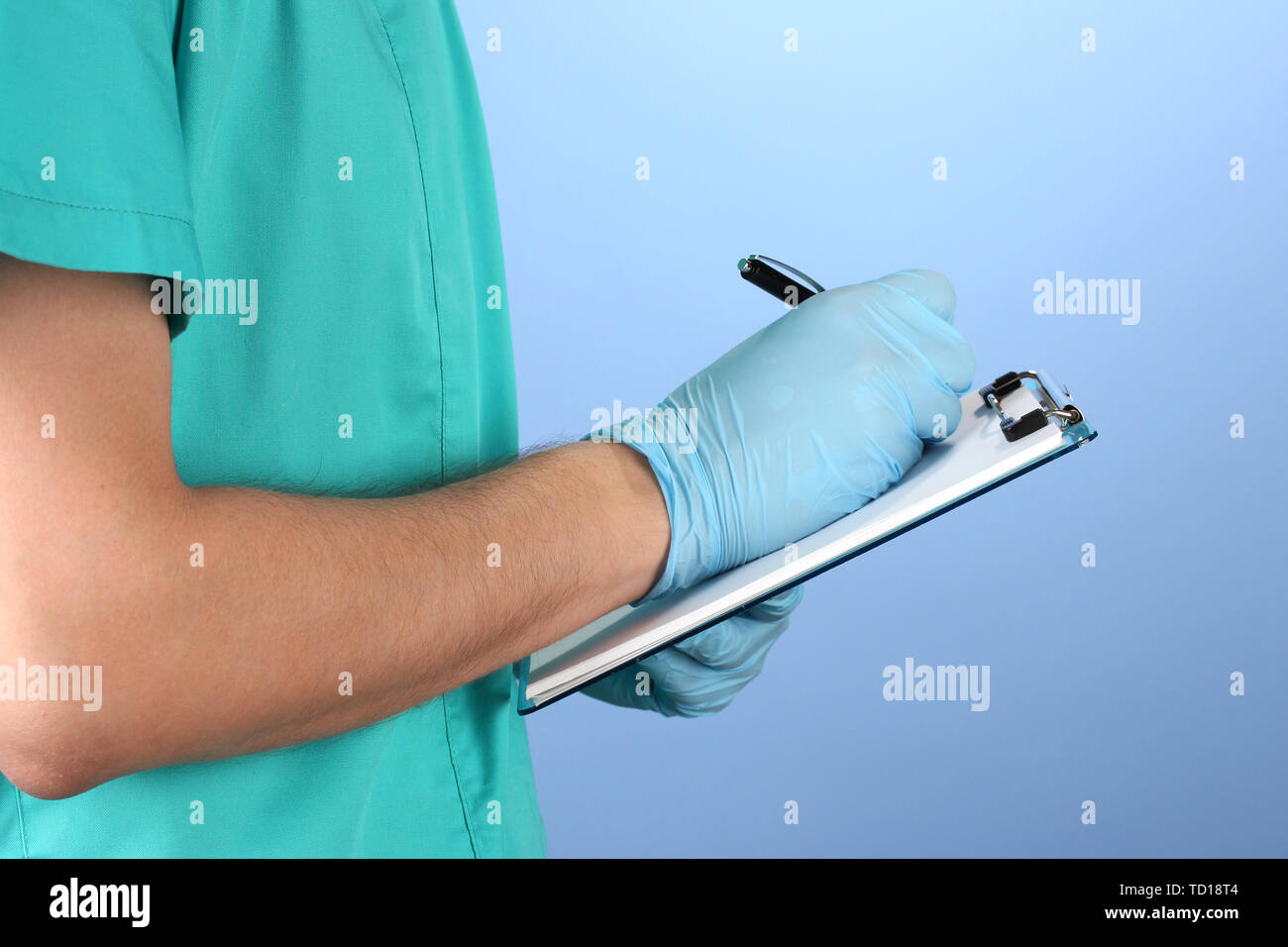 Hand of doctor with pen writing on prescription blank, on blue ...