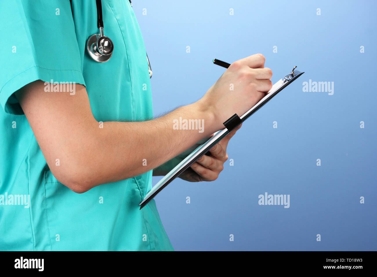 Hand of doctor with pen writing on prescription blank, on blue ...