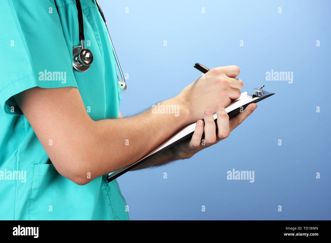 Hand of doctor with pen writing on prescription blank, on blue ...