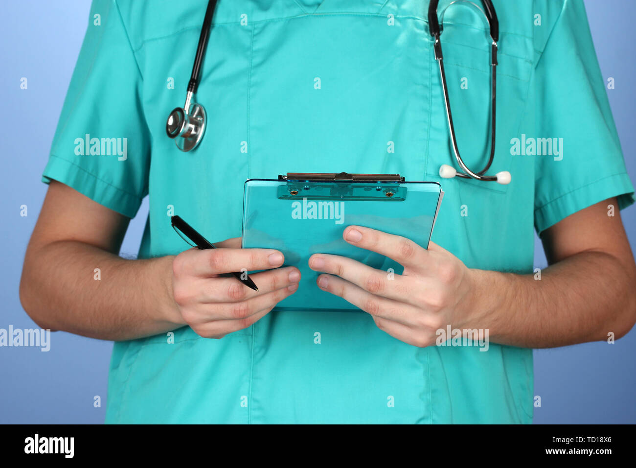 Hand of doctor with pen writing on prescription blank, on blue ...