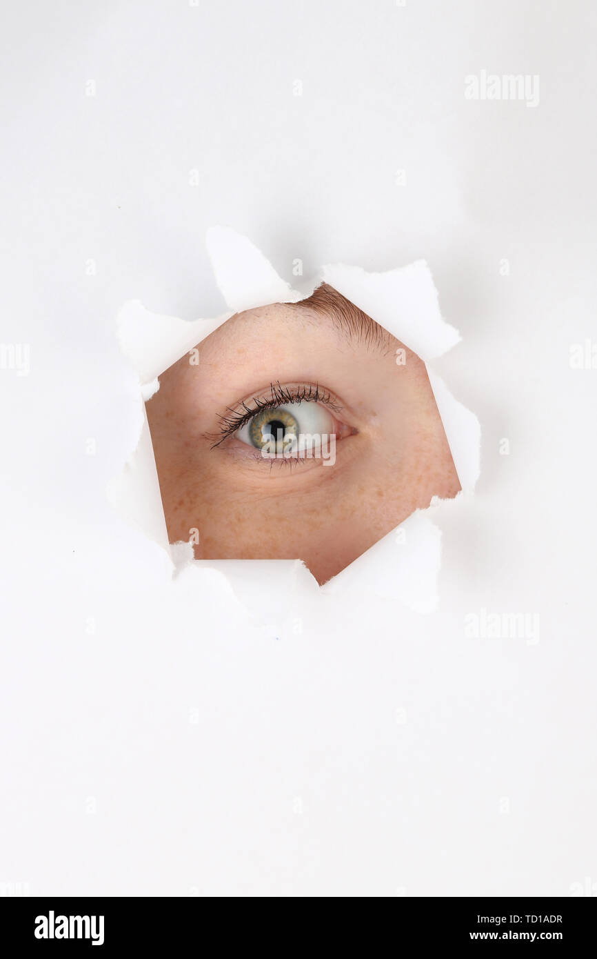 Female eye looking through hole in sheet of paper Stock Photo - Alamy