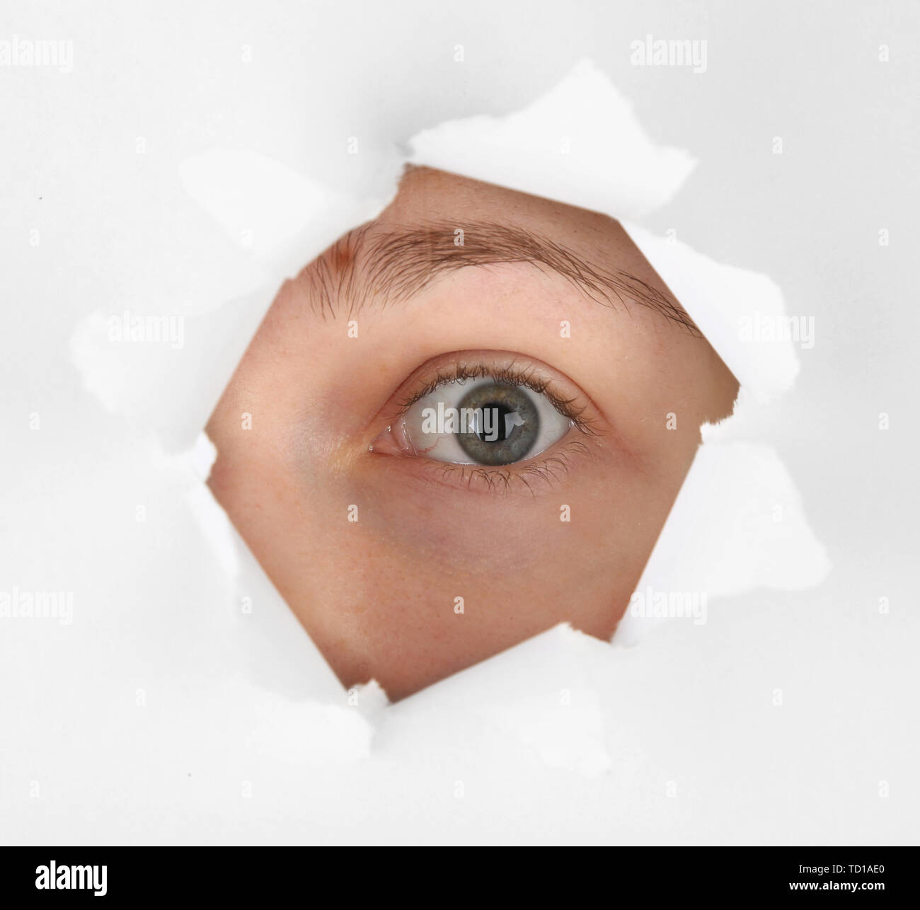 Female eye looking through hole in sheet of paper Stock Photo - Alamy