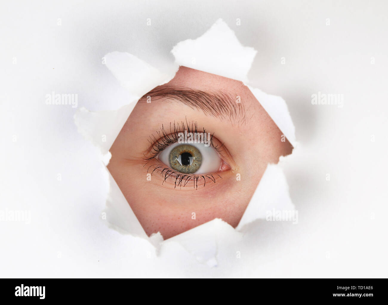 Female eye looking through hole in sheet of paper Stock Photo - Alamy
