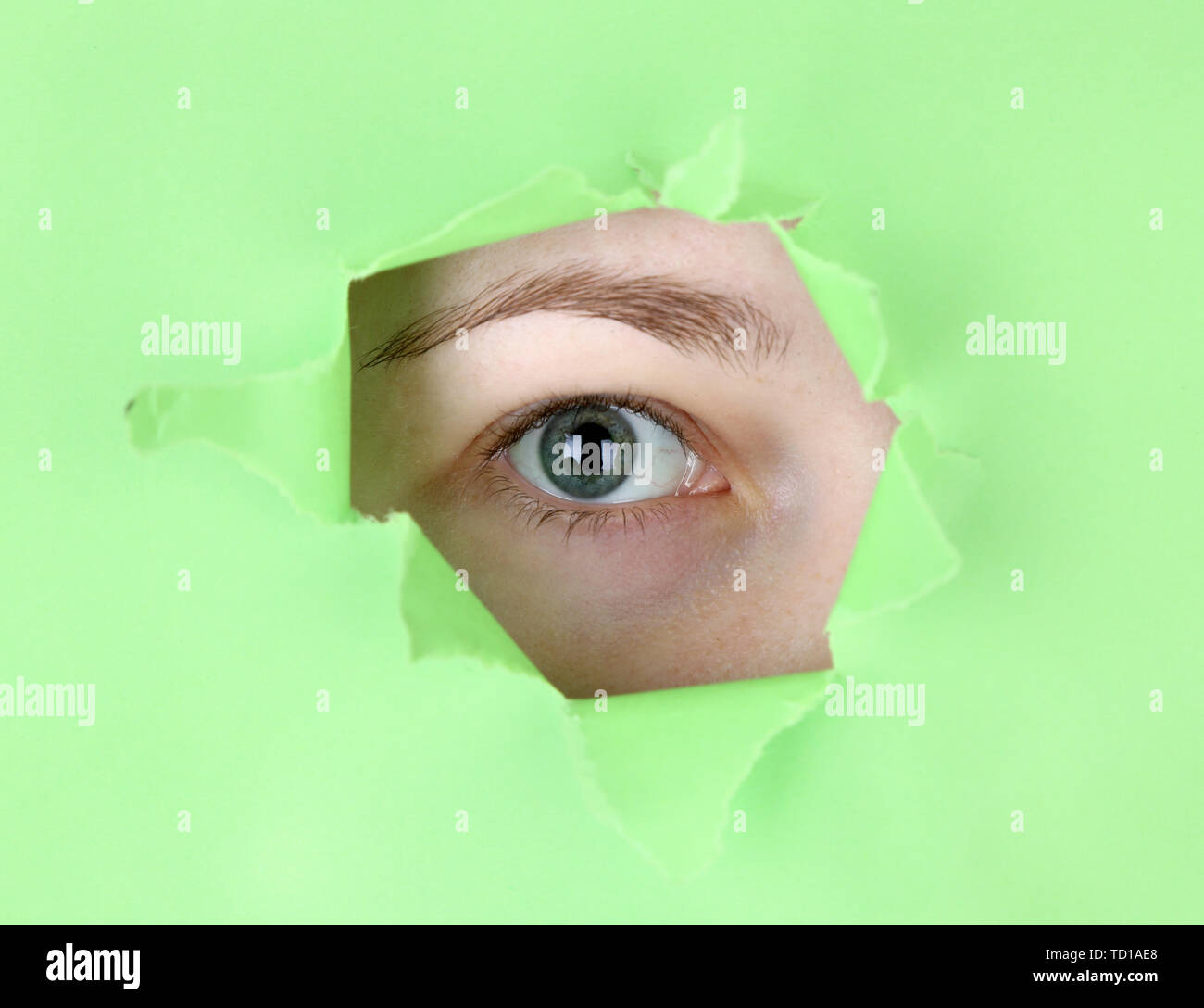 Female eye looking through hole in sheet of paper Stock Photo - Alamy