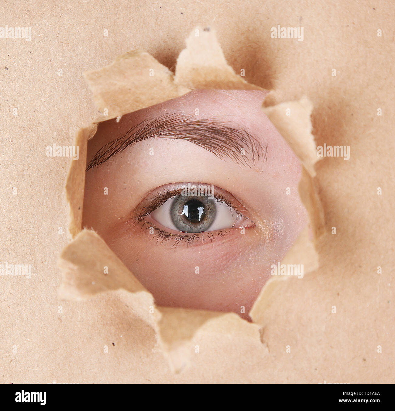Female eye looking through hole in sheet of paper Stock Photo - Alamy