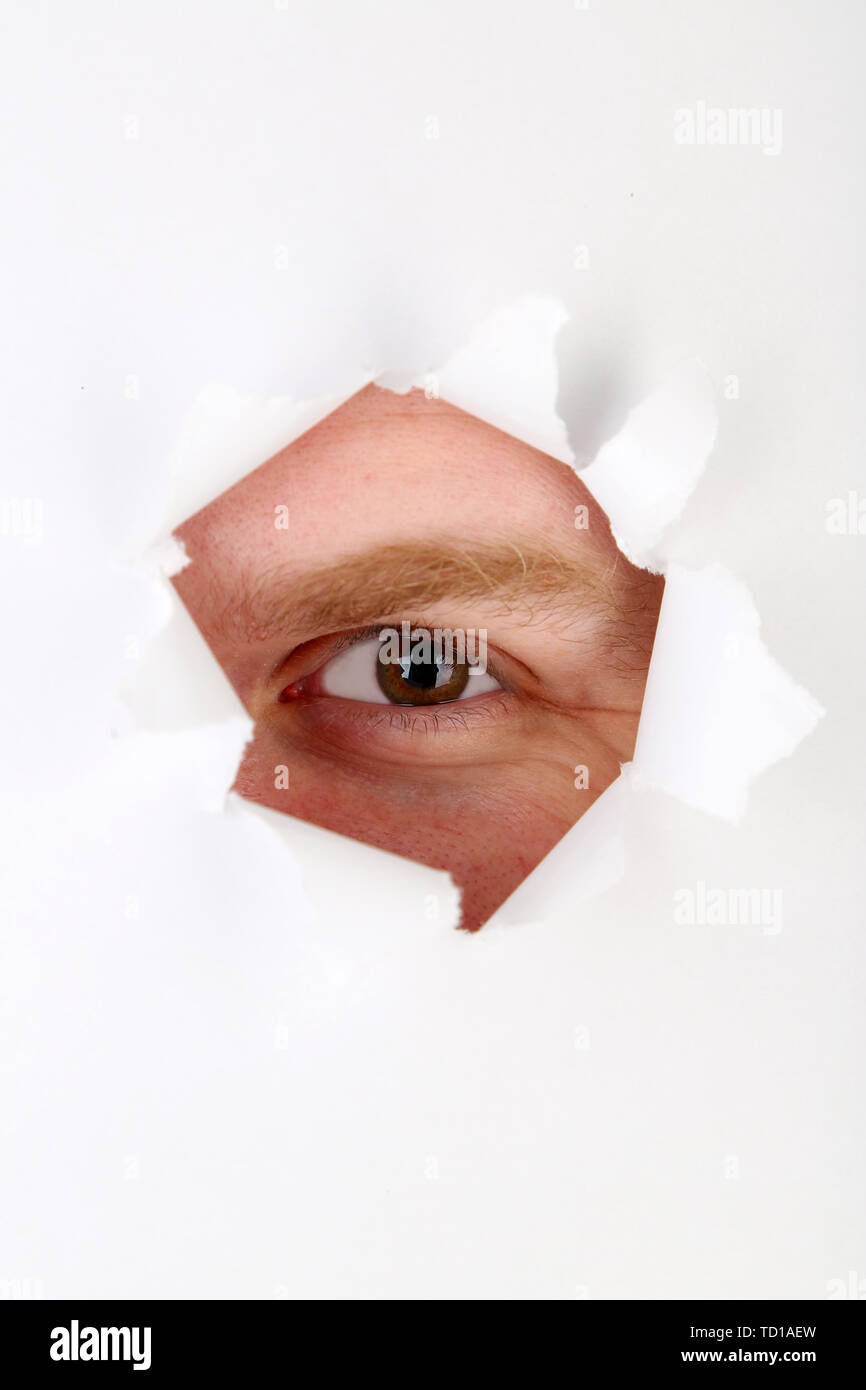 Man eye looking through hole in sheet of paper Stock Photo - Alamy
