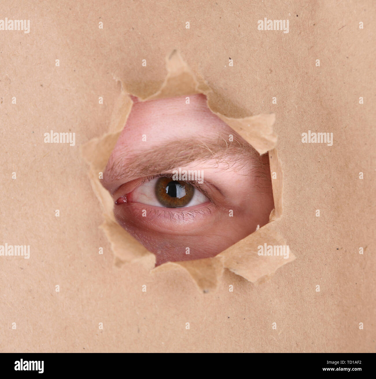 Man eye looking through hole in sheet of paper Stock Photo - Alamy