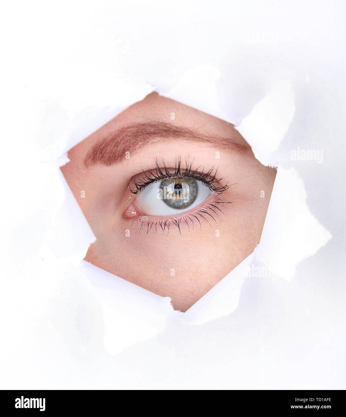 Female eye looking through hole in sheet of paper Stock Photo - Alamy