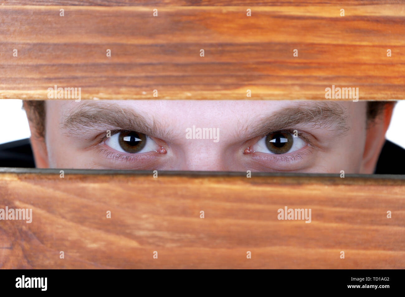 Man eyes looking through hole in wooden desk Stock Photo - Alamy