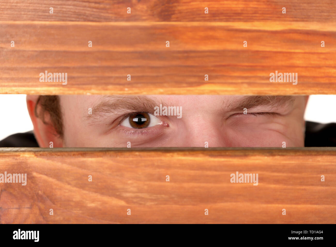 Man eyes looking through hole in wooden desk Stock Photo - Alamy