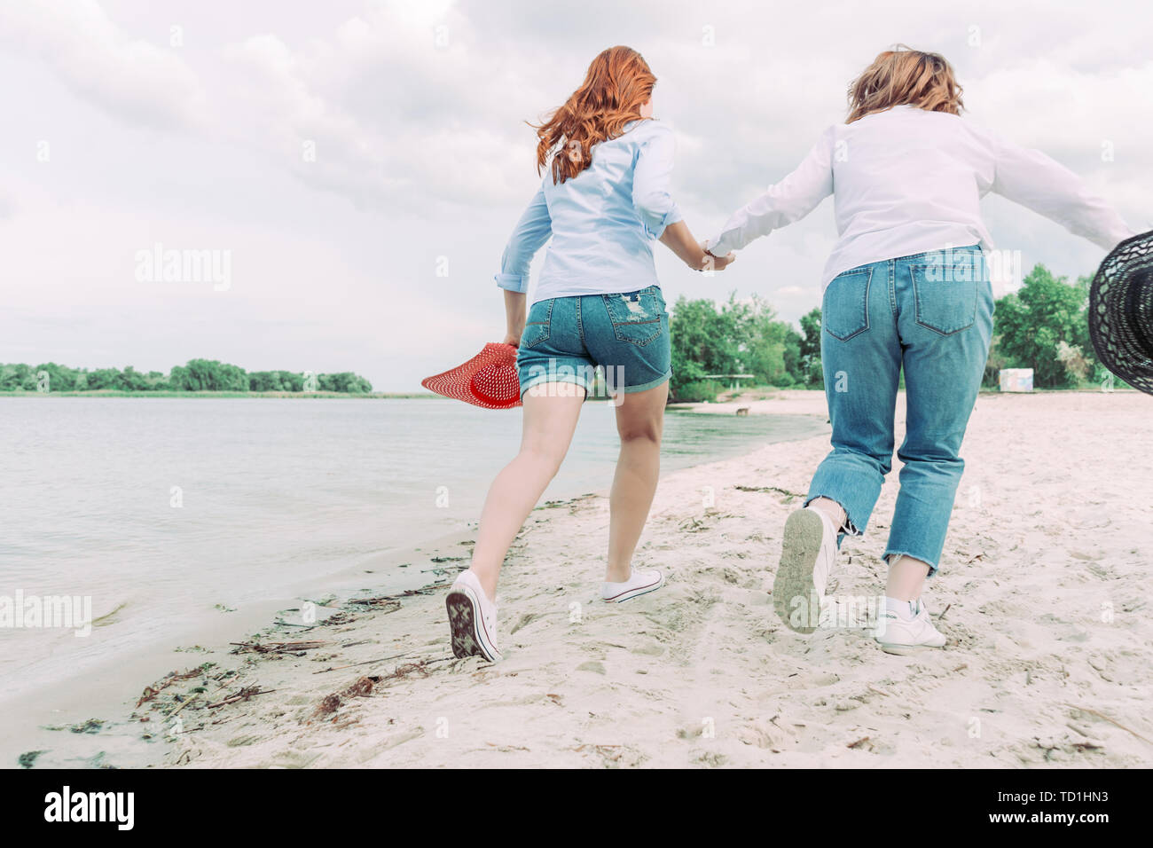 Two young women friends running on the beach. Back view Stock Photo - Alamy