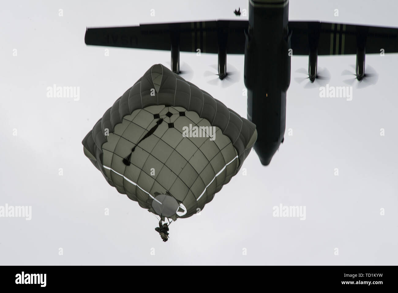 A static-line paratrooper prepares to land as a U.S. Air Force C-130J ...