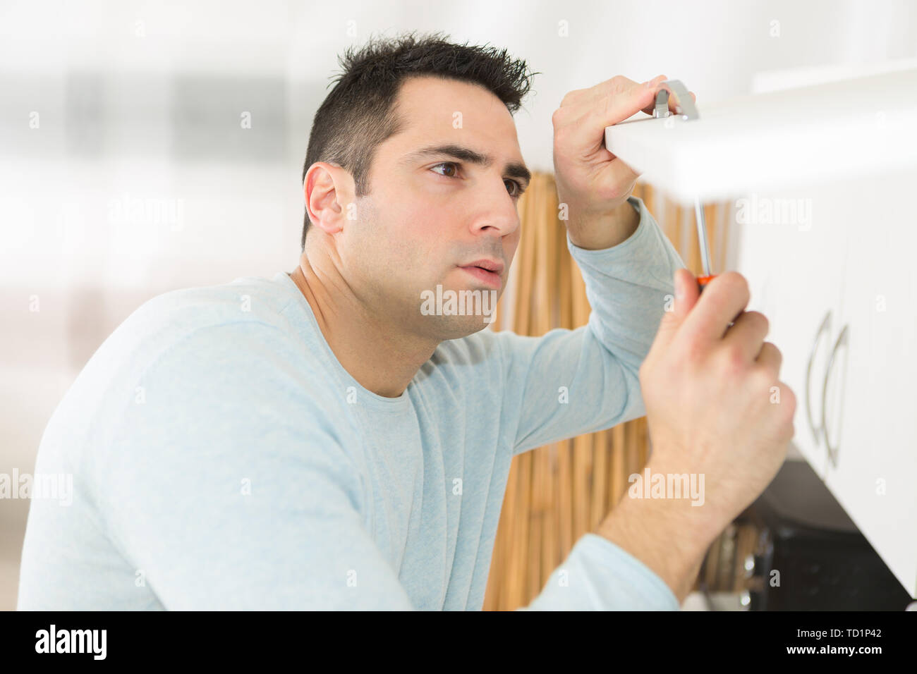 man adjusting the cupboard screws Stock Photo - Alamy