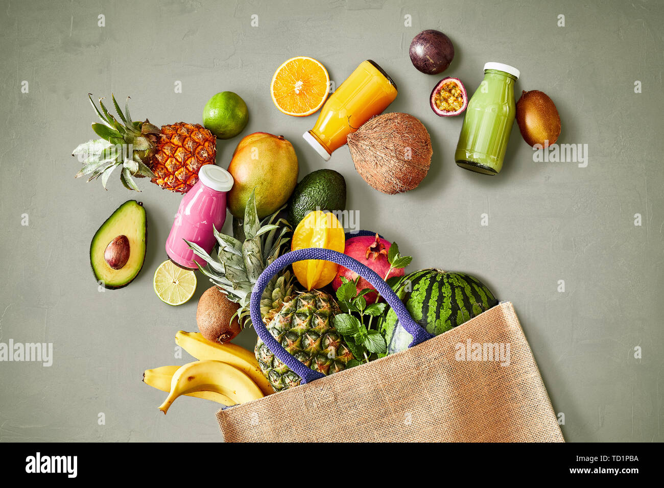 Massive assortment spilled fruit and glass bottles of juice next to bag ...