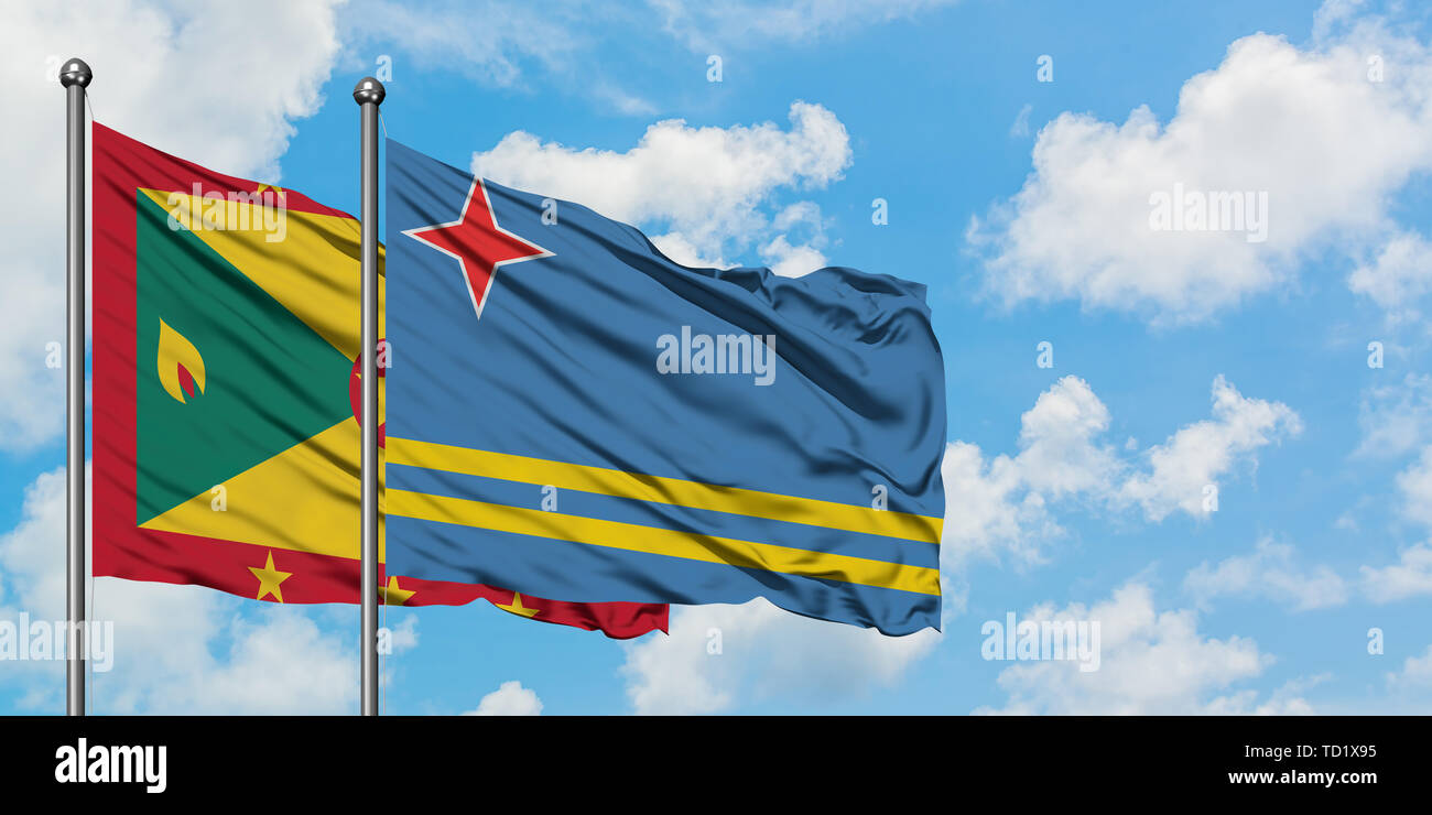 Grenada and Aruba flag waving in the wind against white cloudy blue sky ...