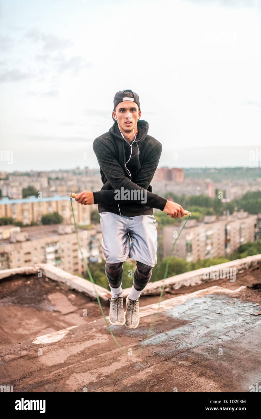 exercising and lifestyle concept - man skipping with jump rope outdoors ...