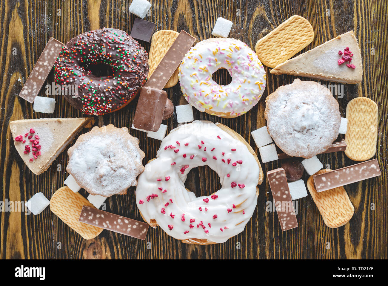 Harmful sweet foods on a dark wooden background. Donuts, muffins ...