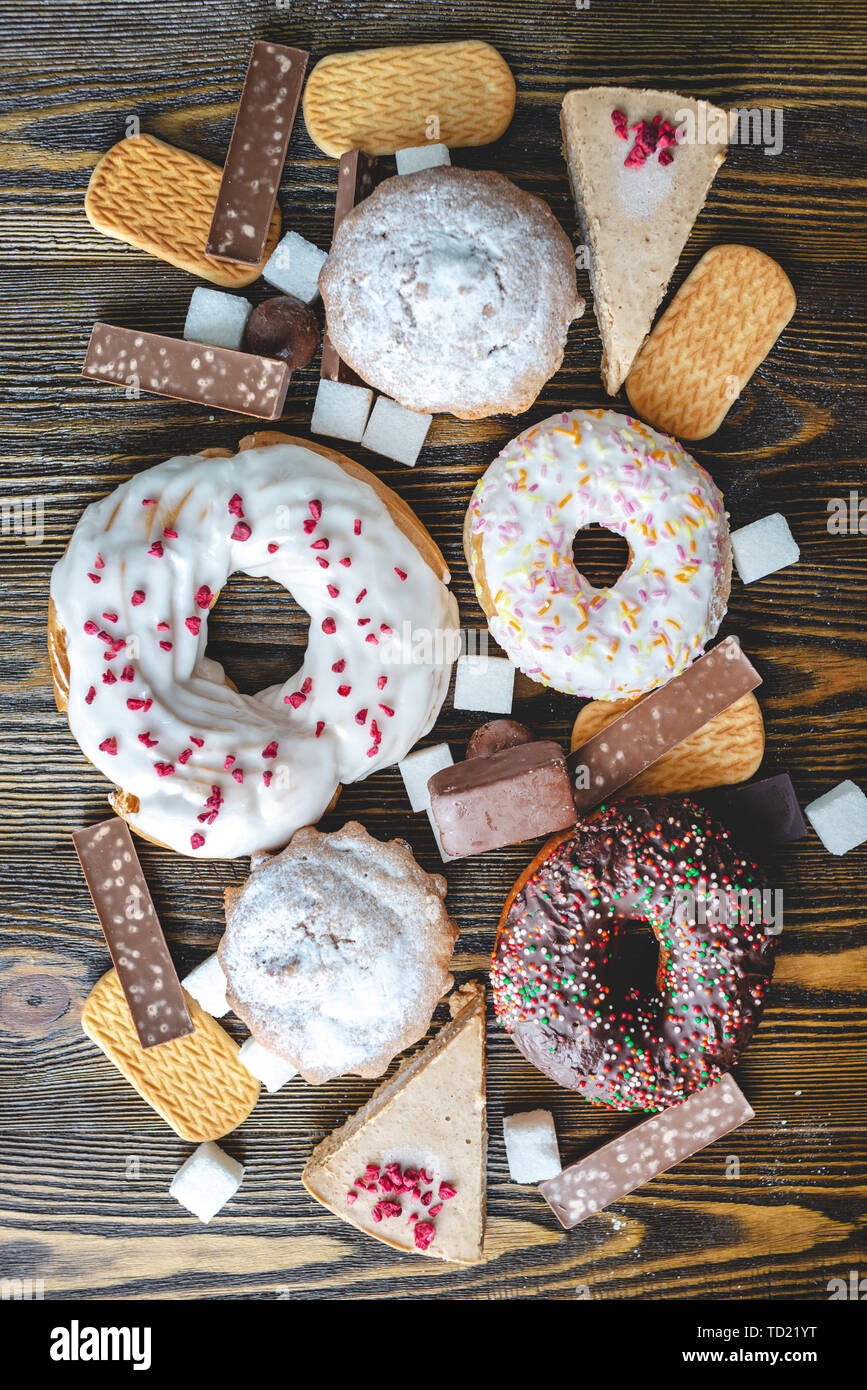 Harmful sweet foods on a dark wooden background. Donuts, muffins ...