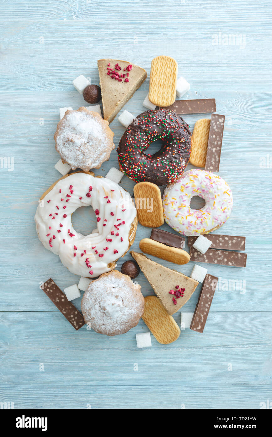 Harmful sweet foods on blue wooden background. Donuts, muffins ...