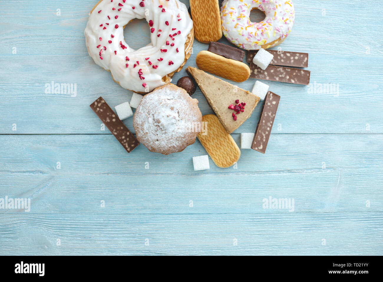 Harmful sweet foods on blue wooden background. Donuts, muffins ...