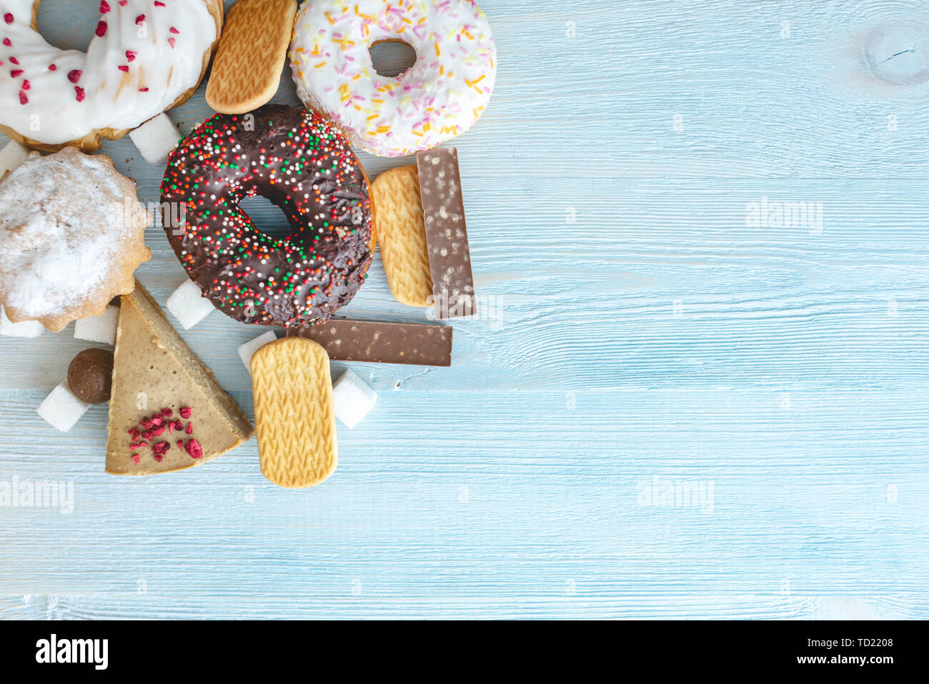 Harmful sweet foods on blue wooden background. Donuts, muffins ...