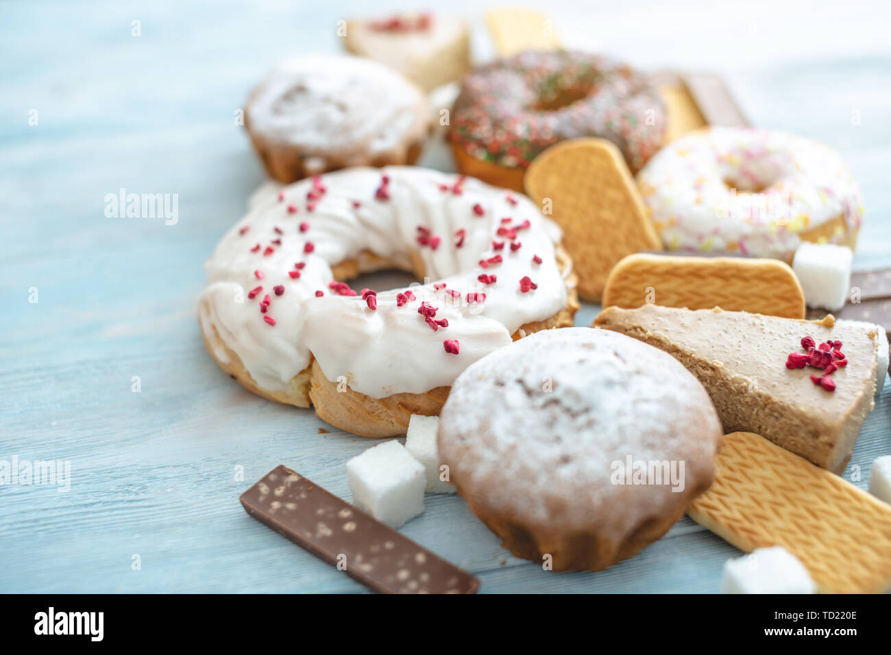 Harmful sweet foods on blue wooden background. Donuts, muffins ...