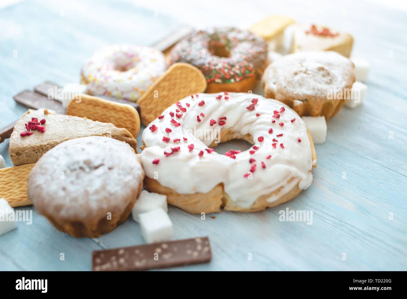 Harmful sweet foods on blue wooden background. Donuts, muffins ...