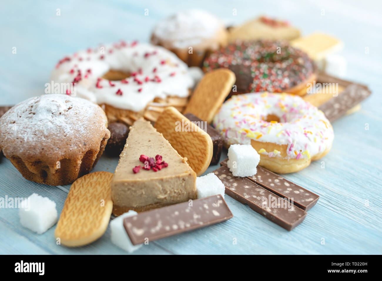 Harmful sweet foods on blue wooden background. Donuts, muffins ...