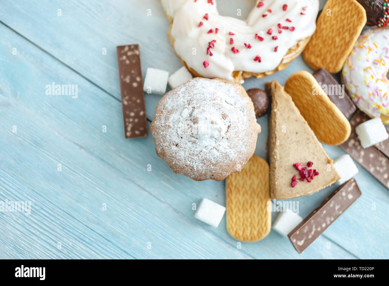 Harmful sweet foods on blue wooden background. Donuts, muffins ...